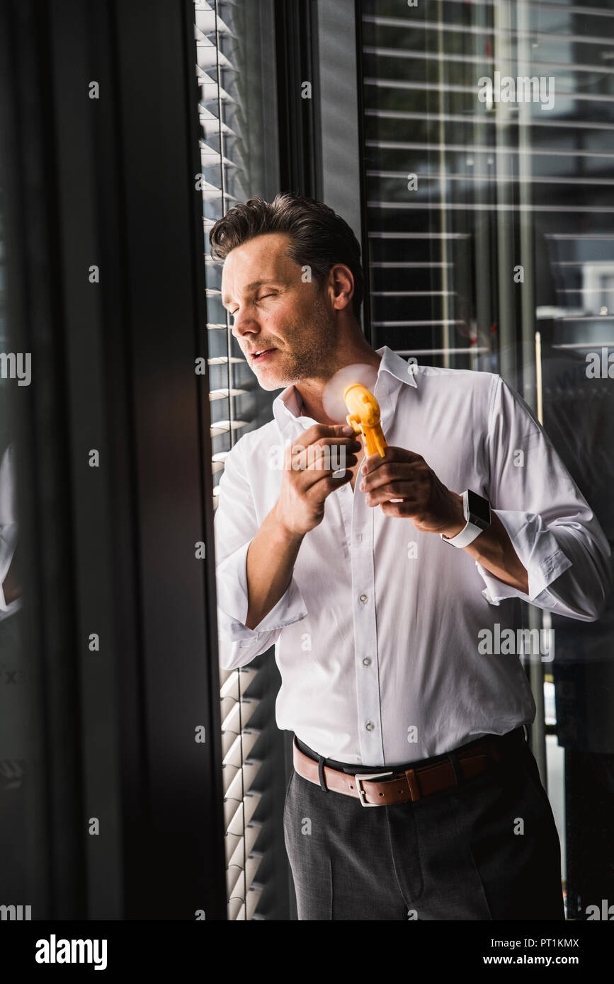 Businessman using hand fan at the window in office Stock Photo - Alamy