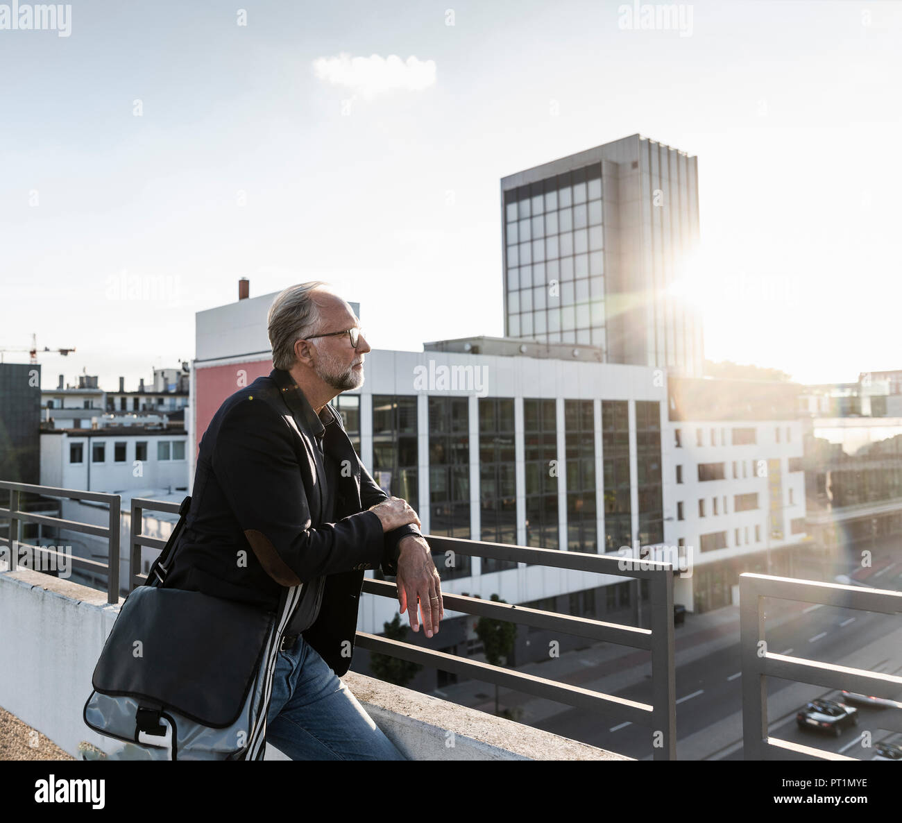 Mature man standing on rooftop, leaning on railing Stock Photo - Alamy