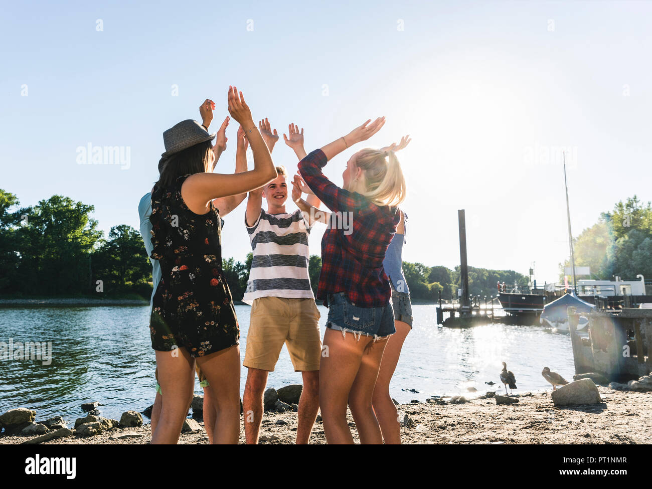 Group of friends raising their hands at the riverside Stock Photo - Alamy