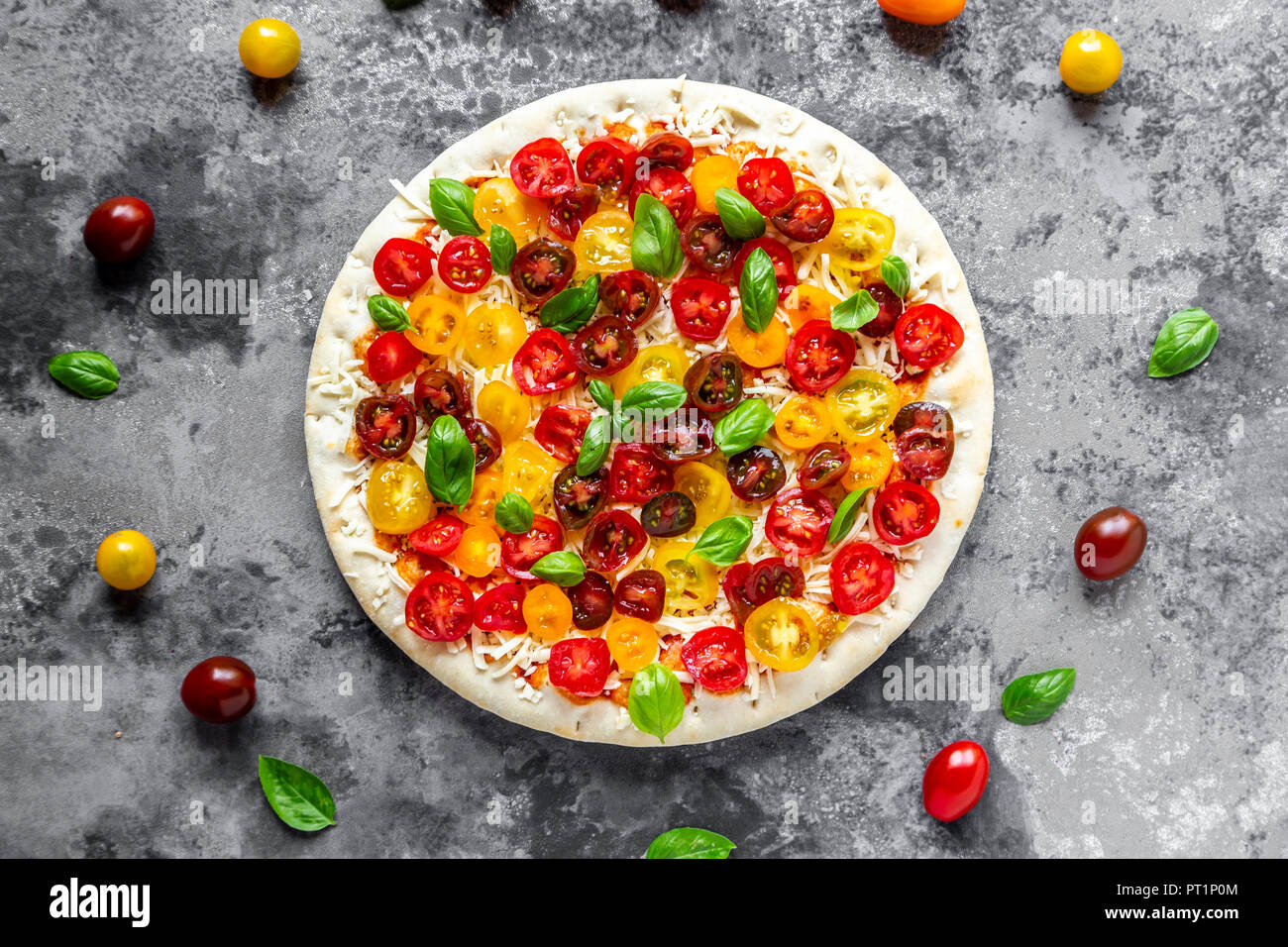 Unbaked pizza with tomatoes and basil leaves Stock Photo - Alamy