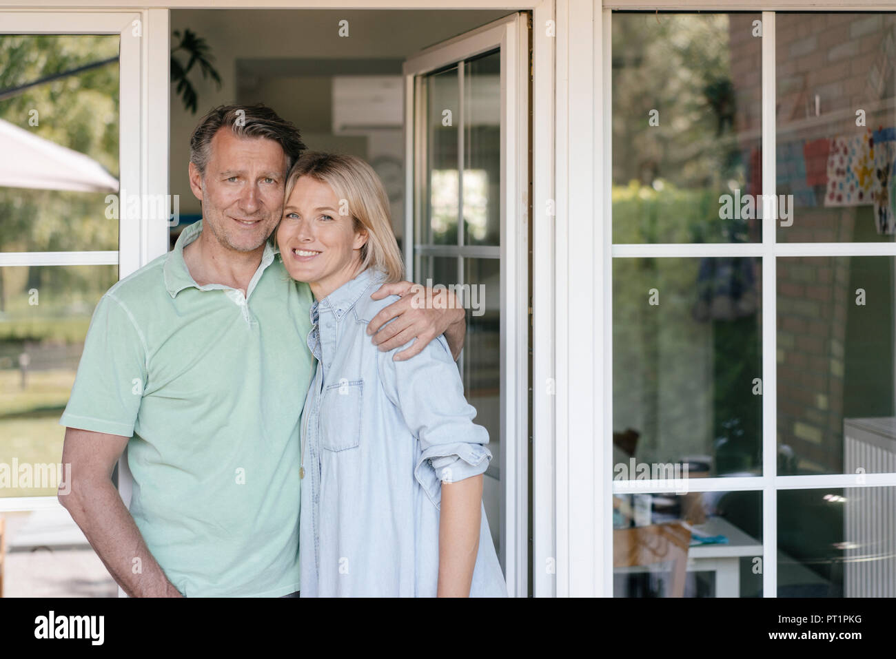 Portrait of smiling mature couple at French window Stock Photo - Alamy