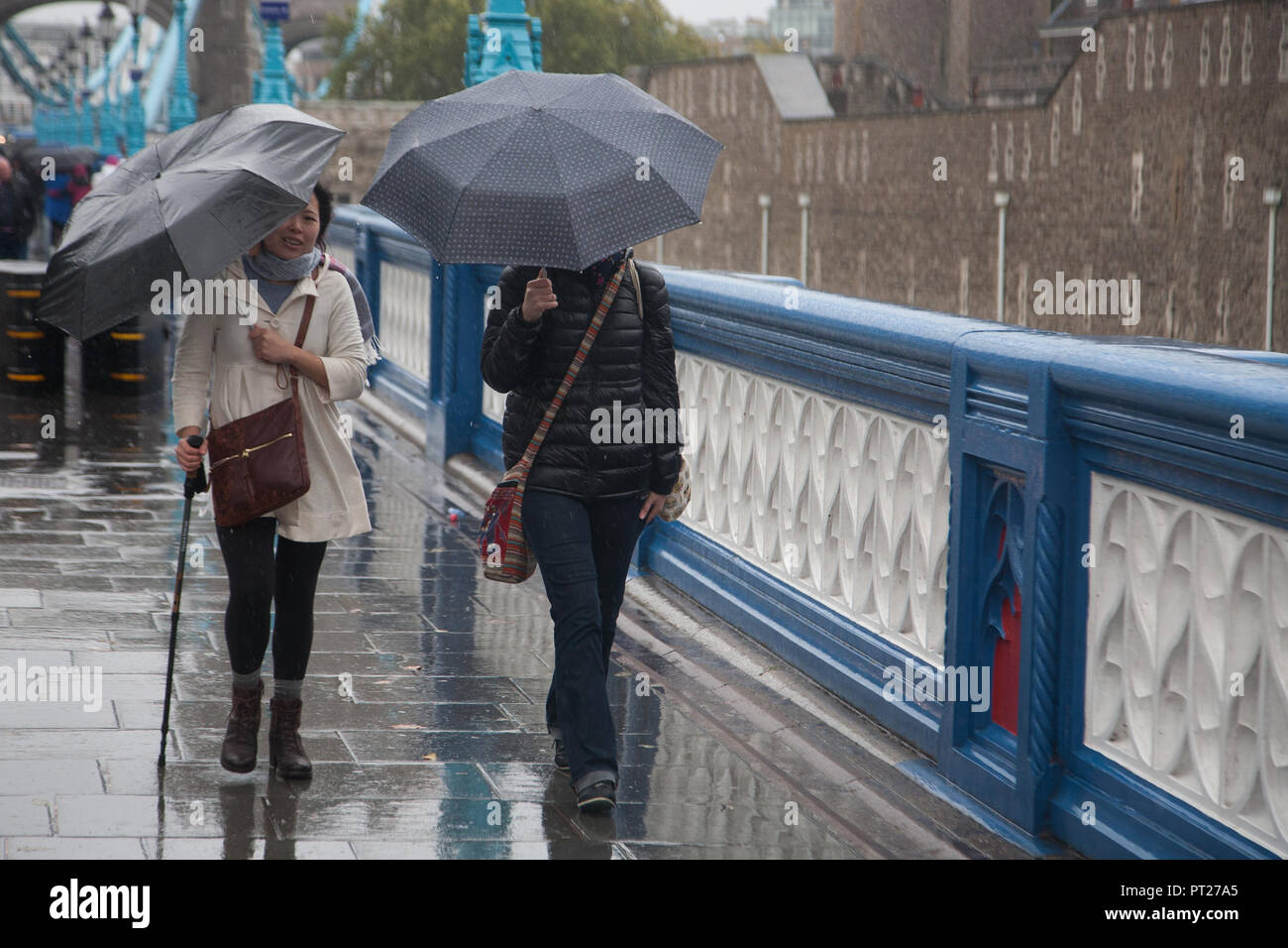 London UK. 6th October 2018. Pedestrians shelter from the heavy rain on ...