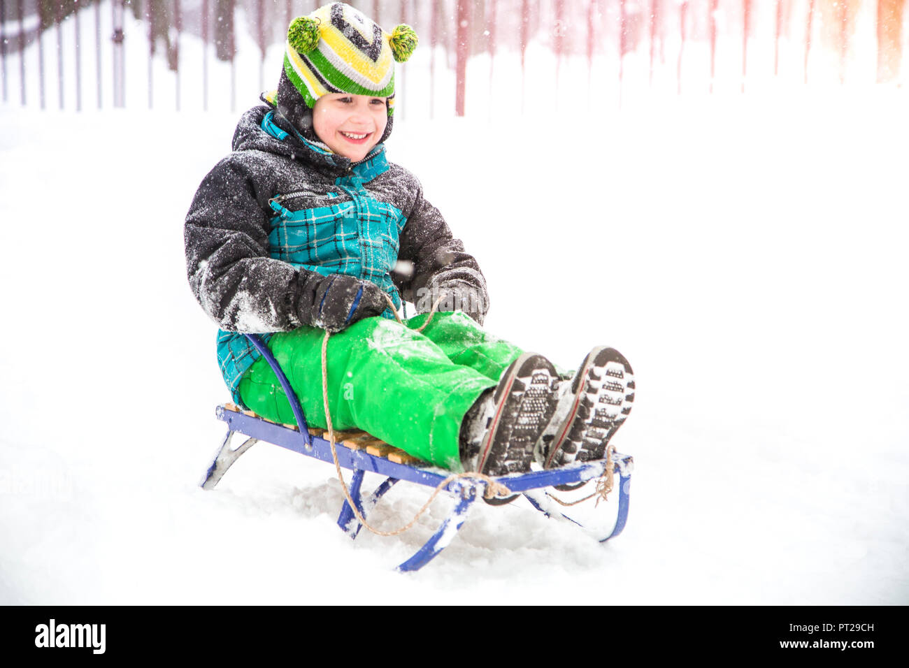 Adorable child boy riding a sled from a snow slide Stock Photo - Alamy