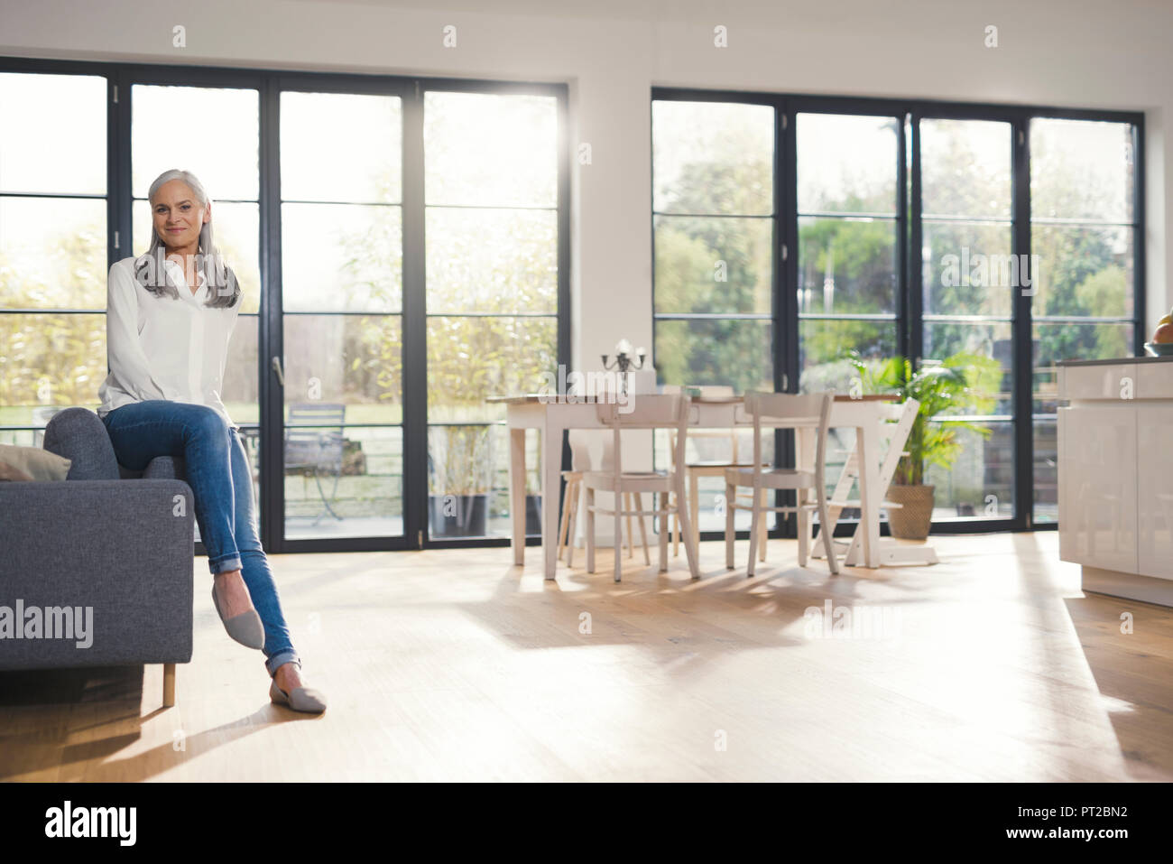 Senior woman standing by couch in living room Stock Photo - Alamy