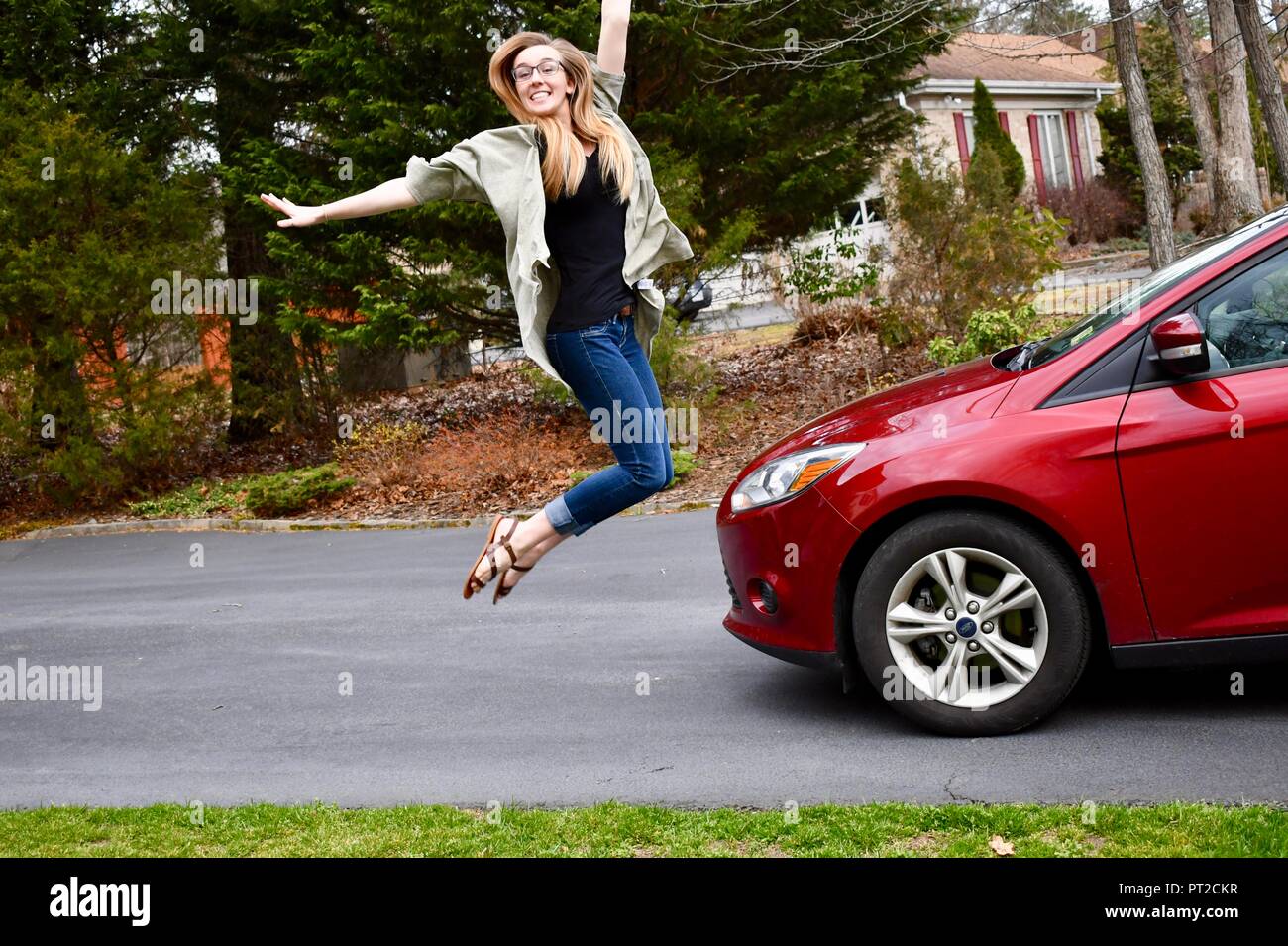 happy blond girl jumping for joy by new car Stock Photo - Alamy