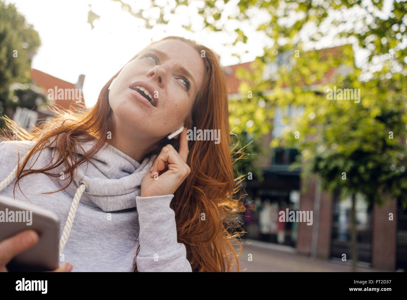 Redheaded woman using earbuds and smartphone Stock Photo - Alamy