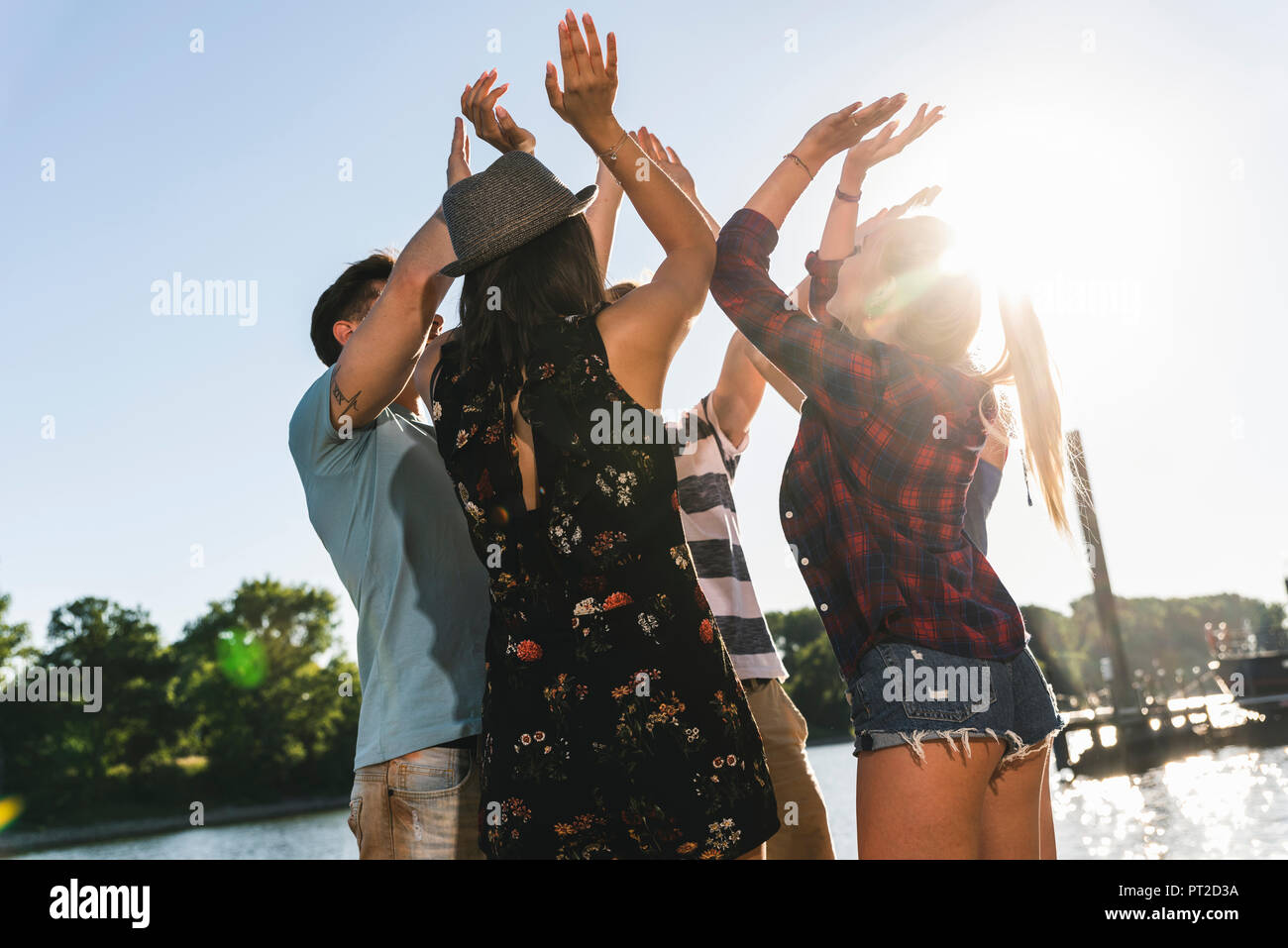 Group of friends raising their hands at the riverside Stock Photo - Alamy