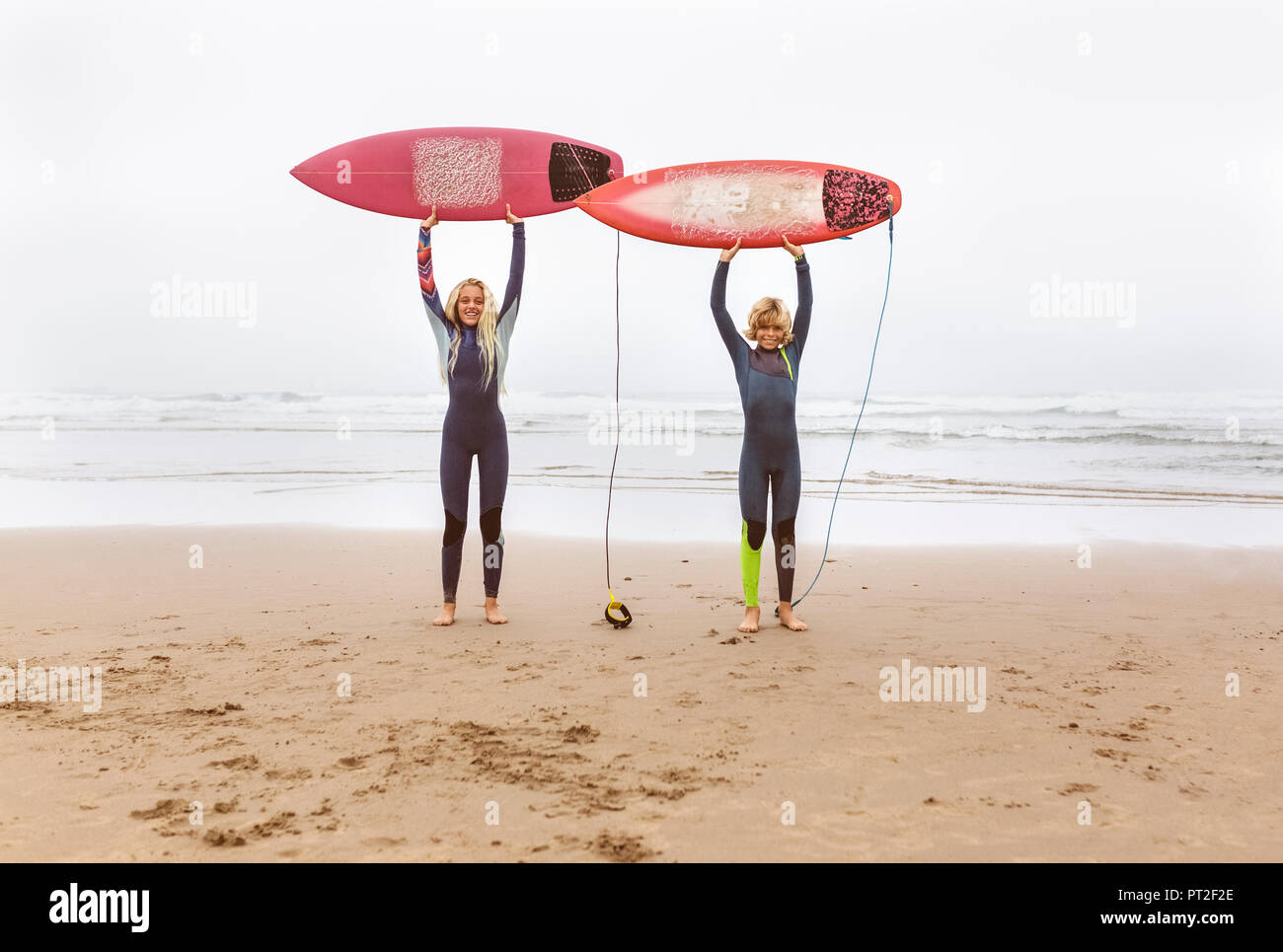 Two young surfers on the beach holding their surfboards hi-res stock ...