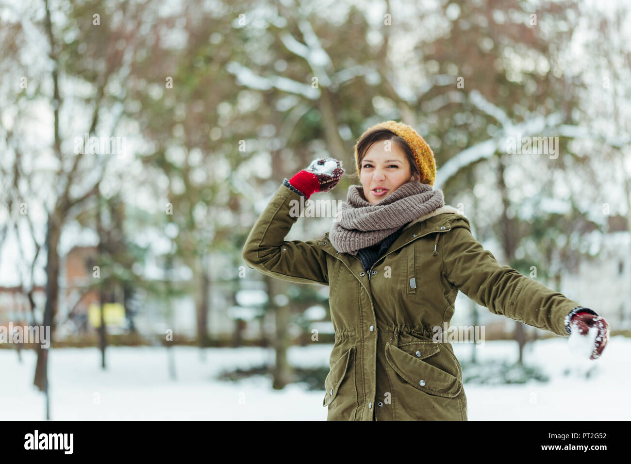Portrait of woman throwing snowball Stock Photo - Alamy