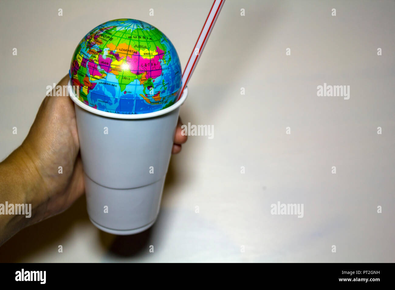 World on a plastic cup and a plastic straw. Plastic pollution concept ...
