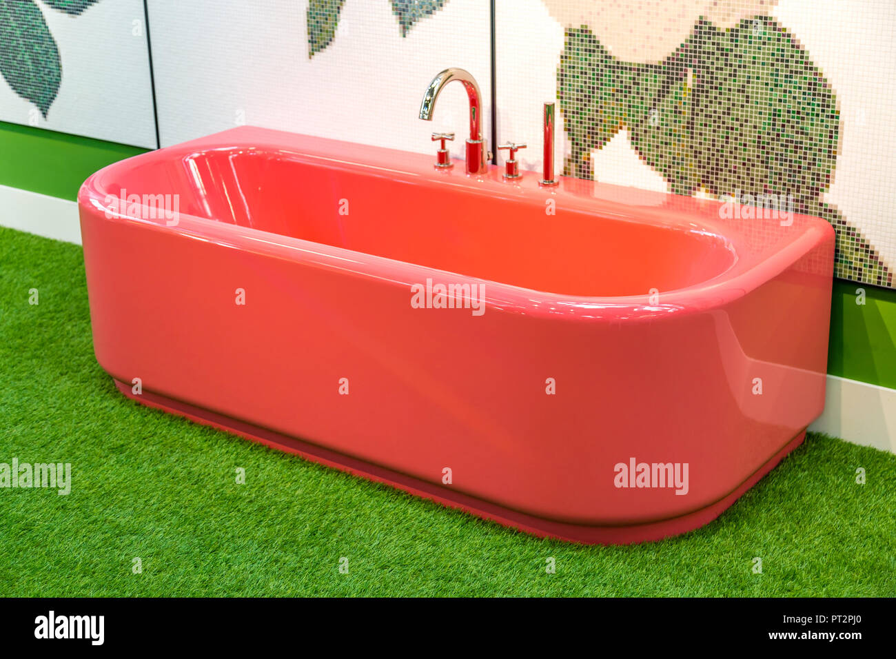 red bathtub on artificial green grass floor Stock Photo - Alamy