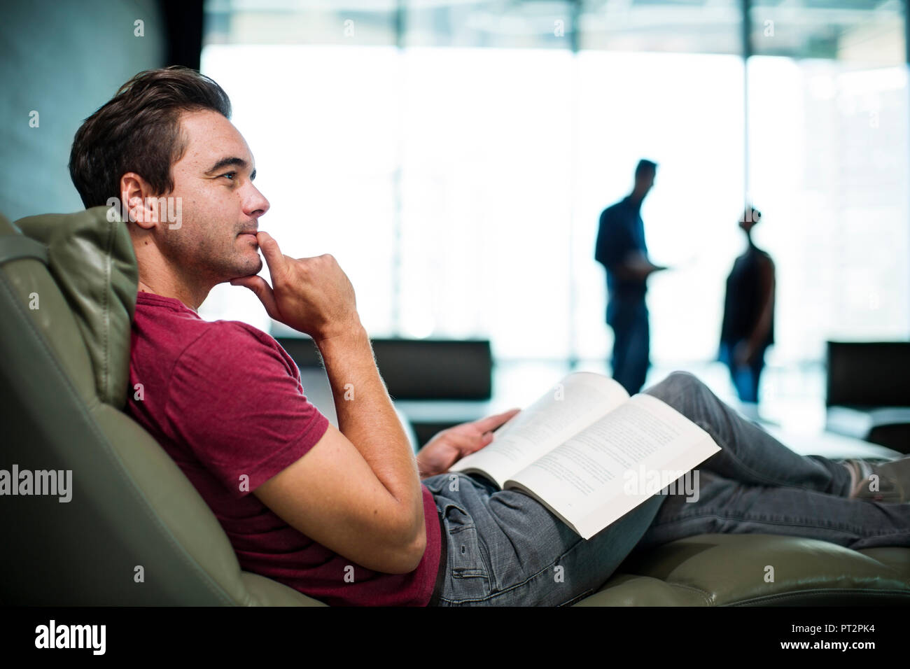 Man in office sitting in armchair, reading a book Stock Photo - Alamy