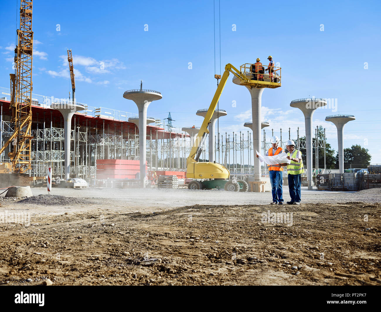 Workers on construction site looking at blueprint with the architect ...