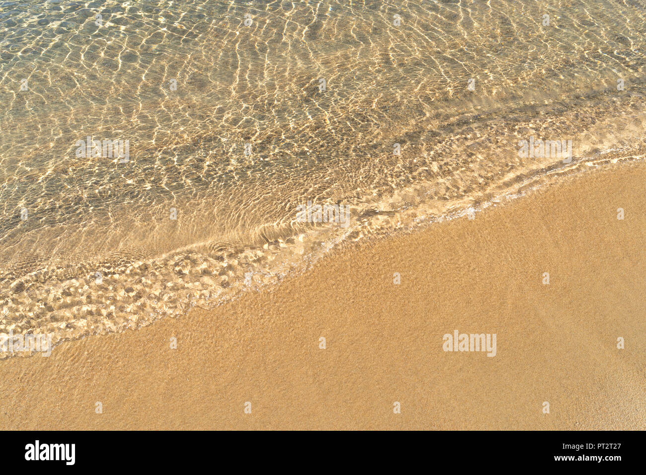 Beachline with bright orange-yellow sand and still transparent sea ...