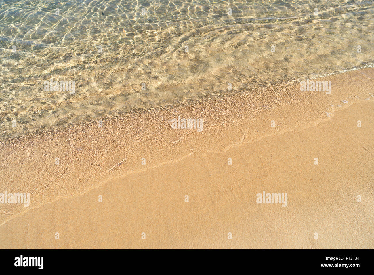 Beachline with bright orange-yellow sand and still transparent sea ...