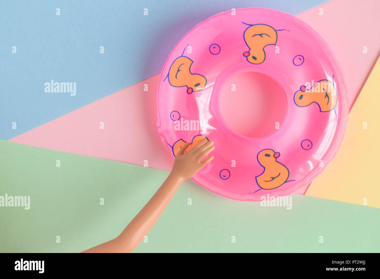 High angle view of doll hand holding inflatable pool float on colorful ...