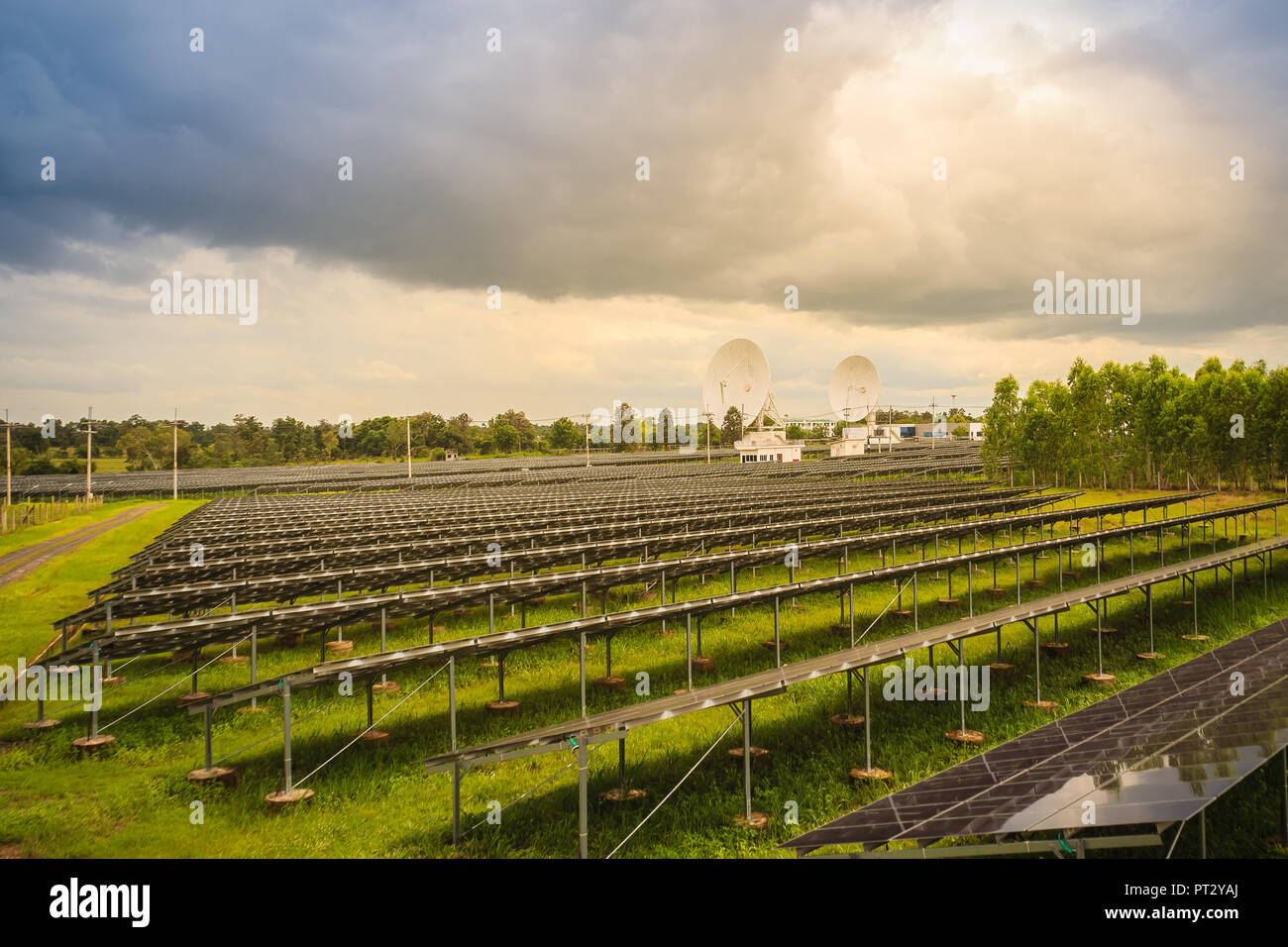 Large scale solar farm with the satellite dishes under dramatic blue ...