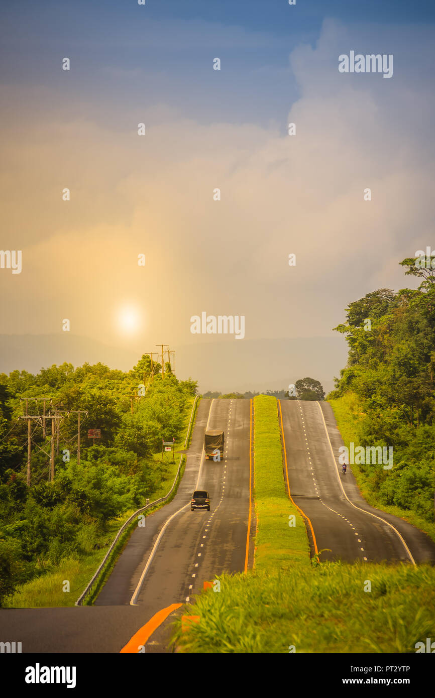 Slope highway with sunshine and green traffic island. Four lane highway ...