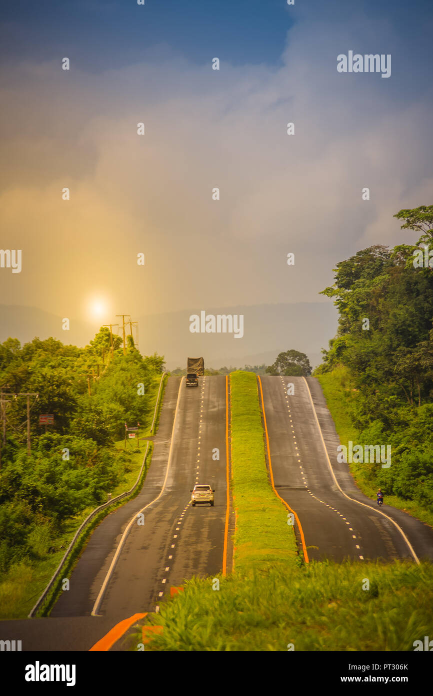 Slope highway with sunshine and green traffic island. Four lane highway ...