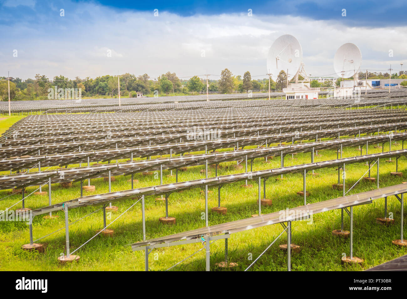 Large scale solar farm with the satellite dishes under dramatic blue ...
