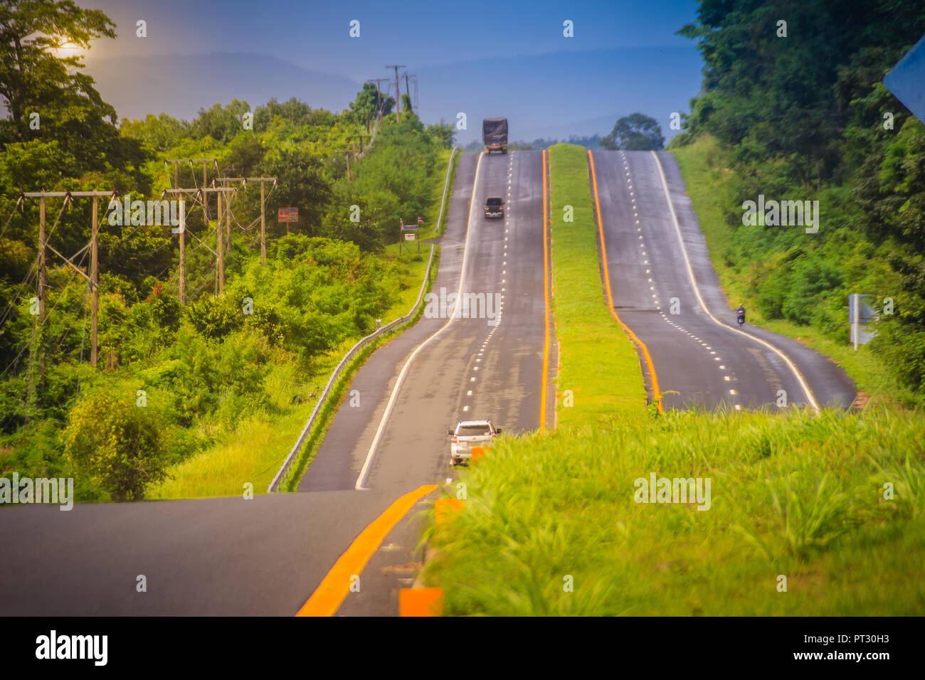 Slope highway with sunshine and green traffic island. Four lane highway ...