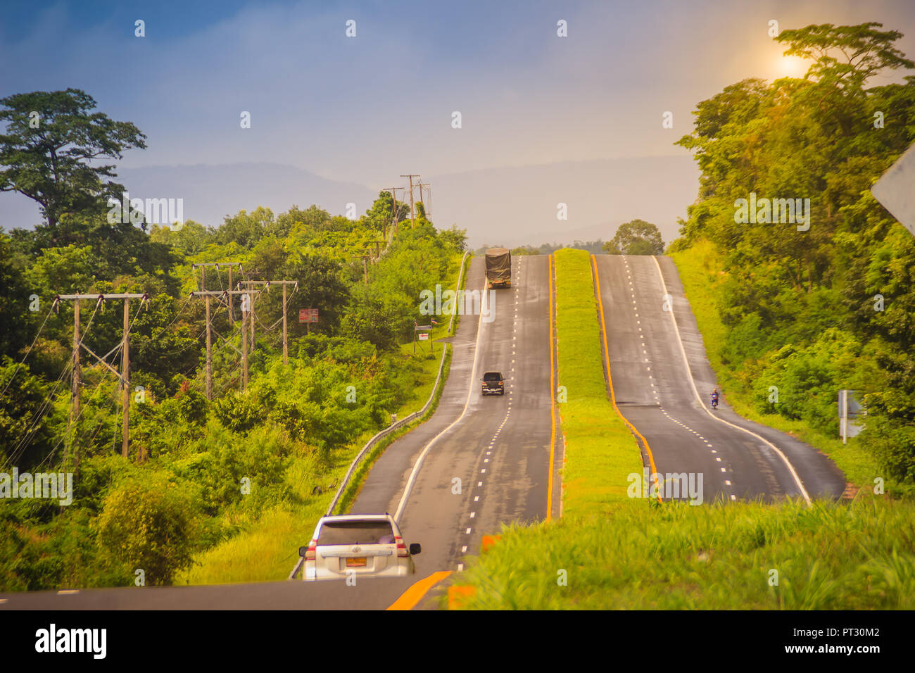 Slope highway with sunshine and green traffic island. Four lane highway ...