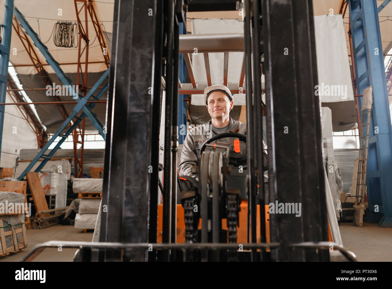 man driving a forklift through a warehouse in a factory. driver in ...