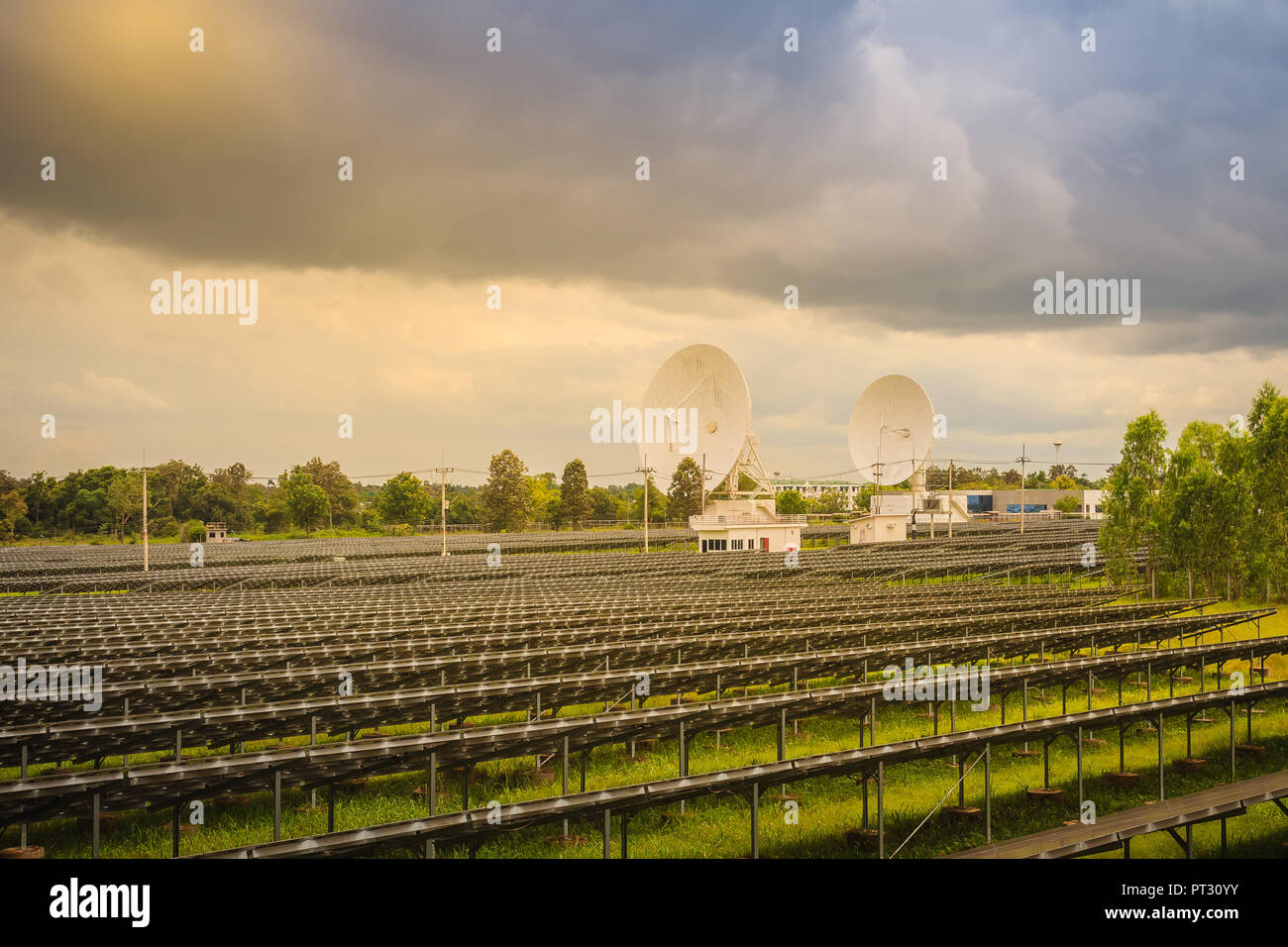 Large scale solar farm with the satellite dishes under dramatic blue ...