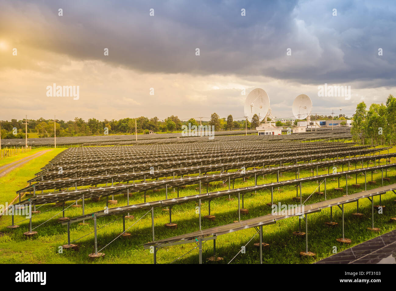 Large scale solar farm with the satellite dishes under dramatic blue ...