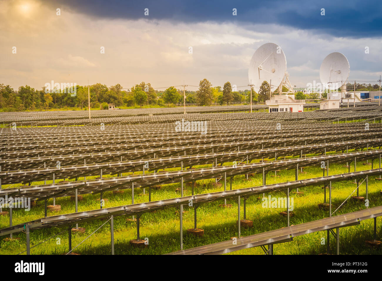 Large scale solar farm with the satellite dishes under dramatic blue ...