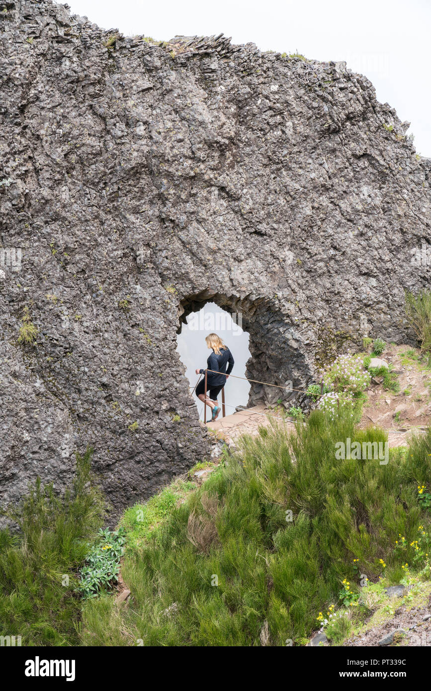 Woman passing through a rock tunnel on the trail at Pico do Areeiro ...