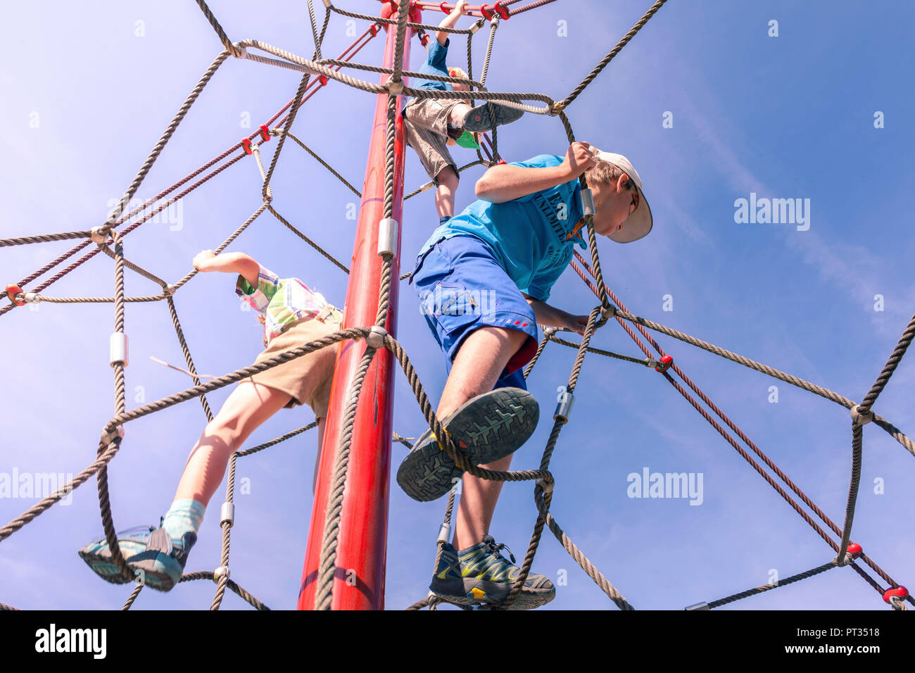 Two boys climbing up a climbing frame on playground hi-res stock ...