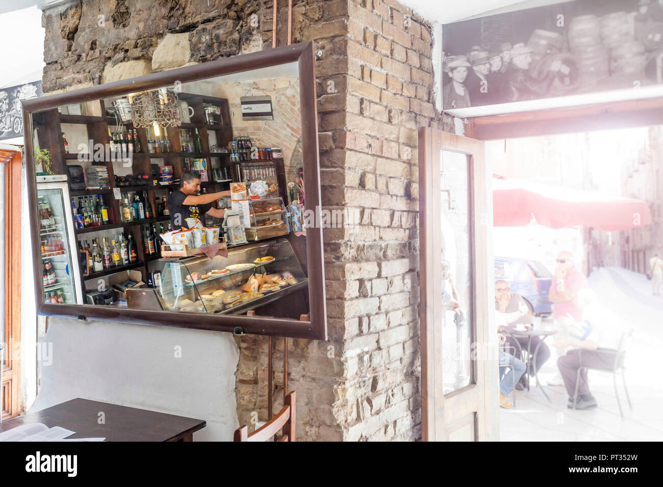 Mirror hanging in cafe showing interior and waiter behind bar, Cagliari ...