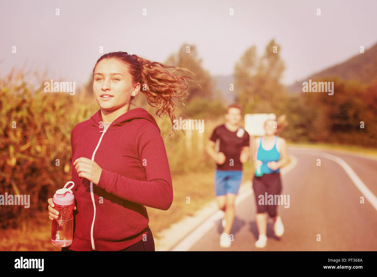group of young people jogging on country road runners running on open ...