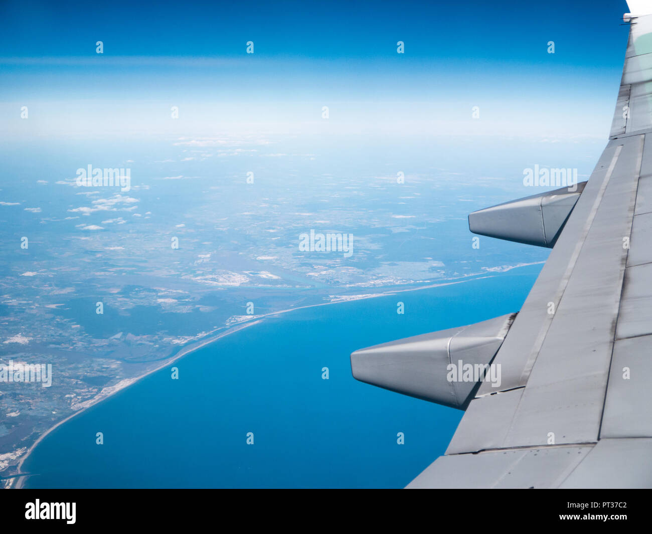 Looking out an airplane window, with blue sky, sea and coastline Stock ...