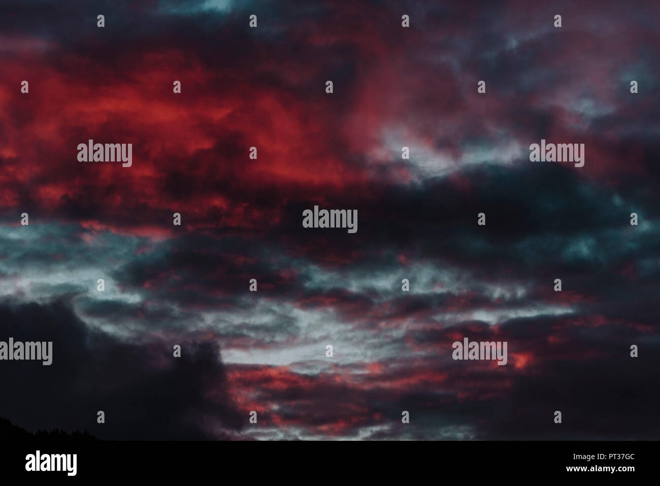 Red evening sun with clouds, blue red clouds Stock Photo - Alamy