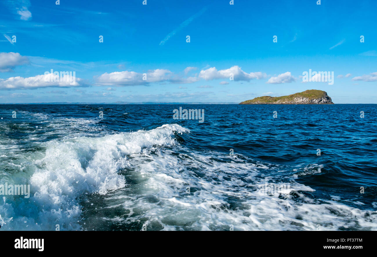Boat wake in Firth of Forth and view of Craigleith Island on sunny day ...