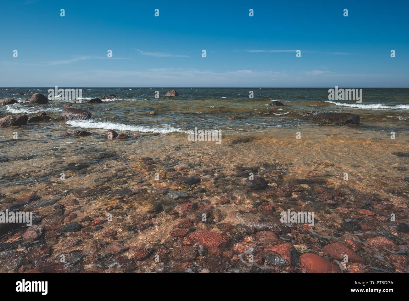rocky sea beach with wide angle perspective over the sea with sunny sky ...