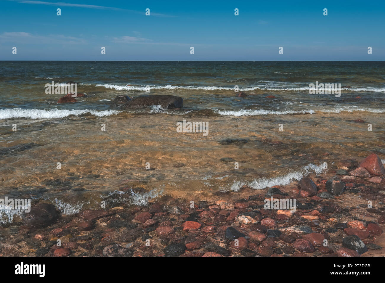 rocky sea beach with wide angle perspective over the sea with sunny sky ...