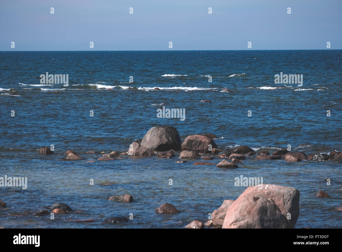rocky sea beach with wide angle perspective over the sea with sunny sky ...
