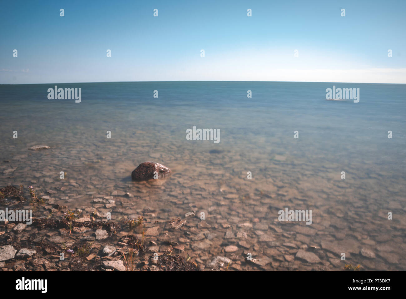 rocky sea beach with wide angle perspective over the sea with sunny sky ...