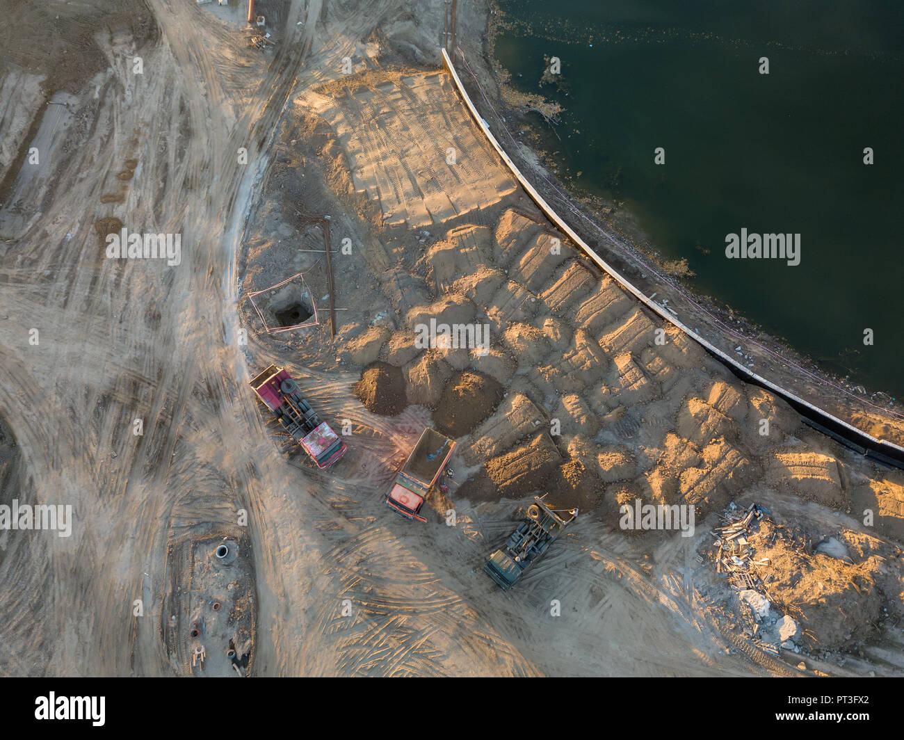 Aerial view of three multi-colored dump tip trucks unloading in a ...