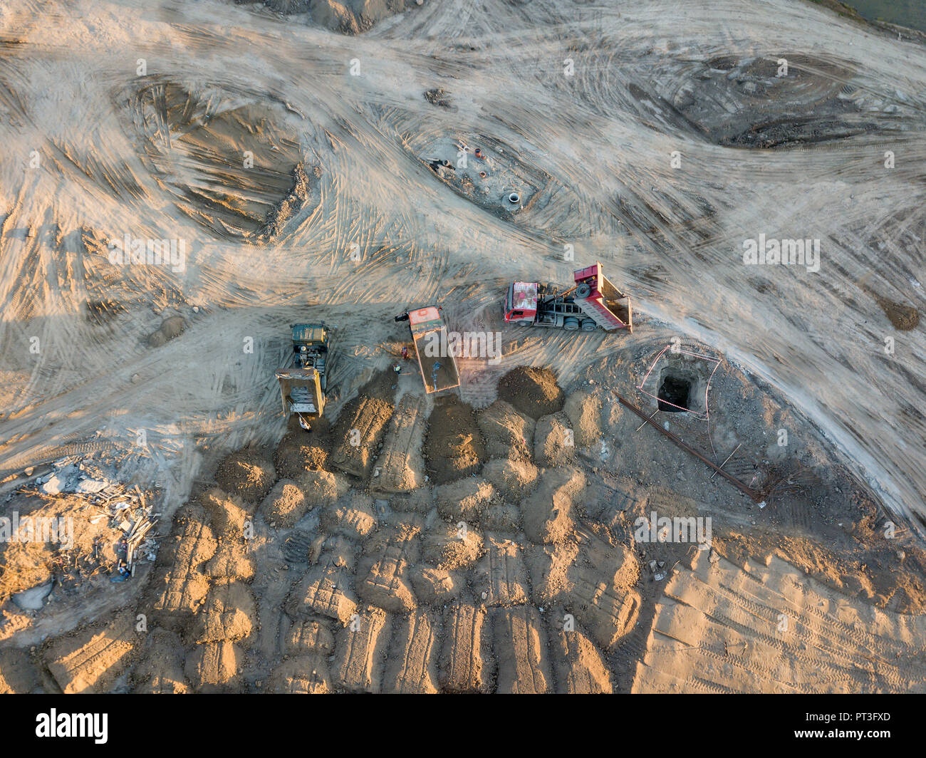 Aerial view of three multi-colored dump tip trucks unloading in a ...