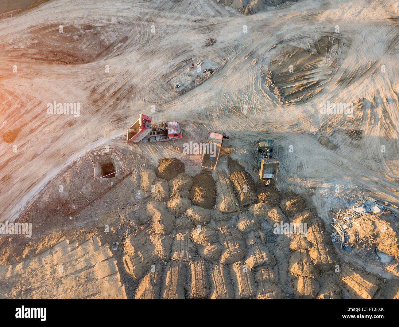 Aerial view of three multi-colored dump tip trucks unloading in a ...
