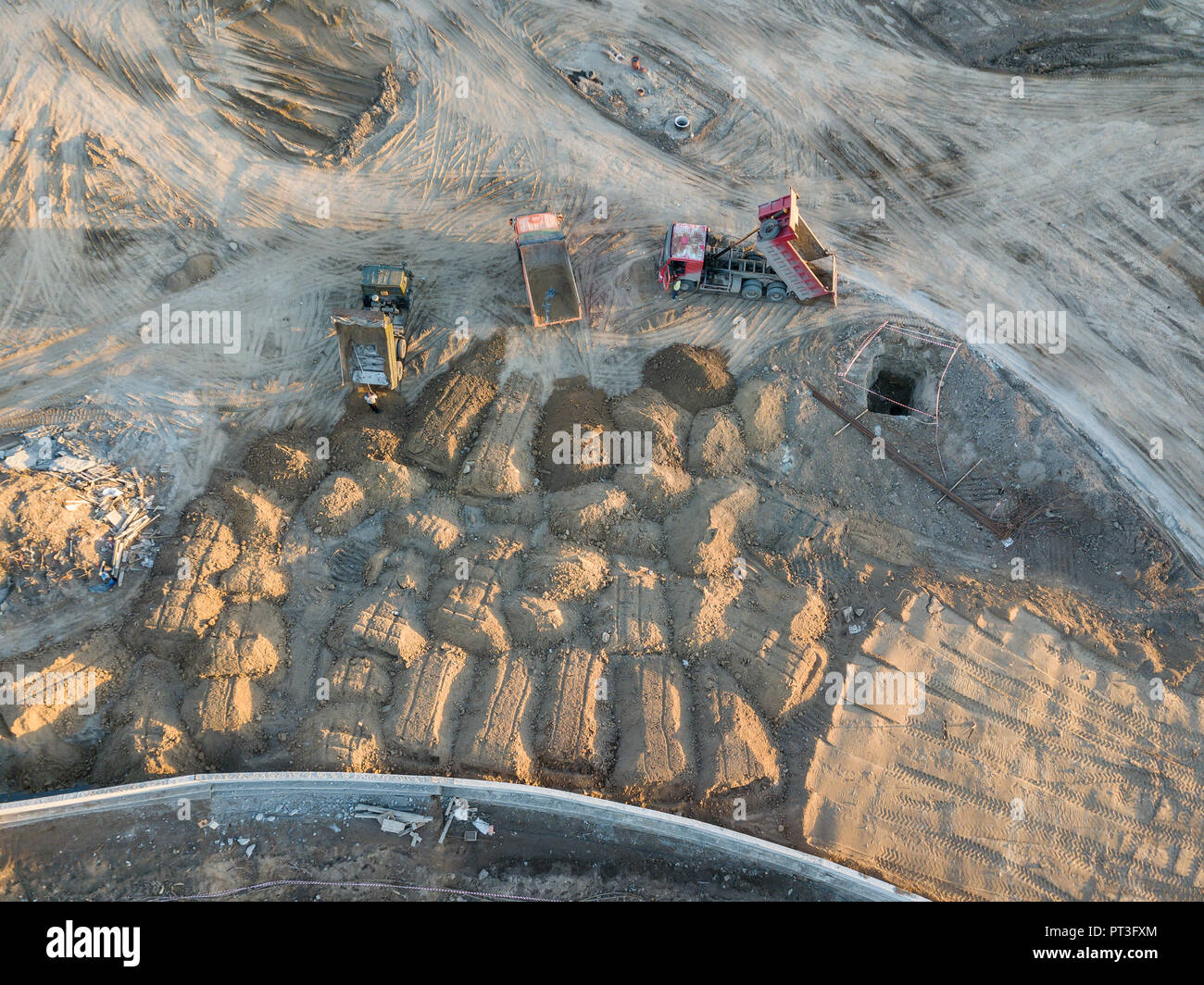 Aerial view of three multi-colored dump tip trucks unloading in a ...