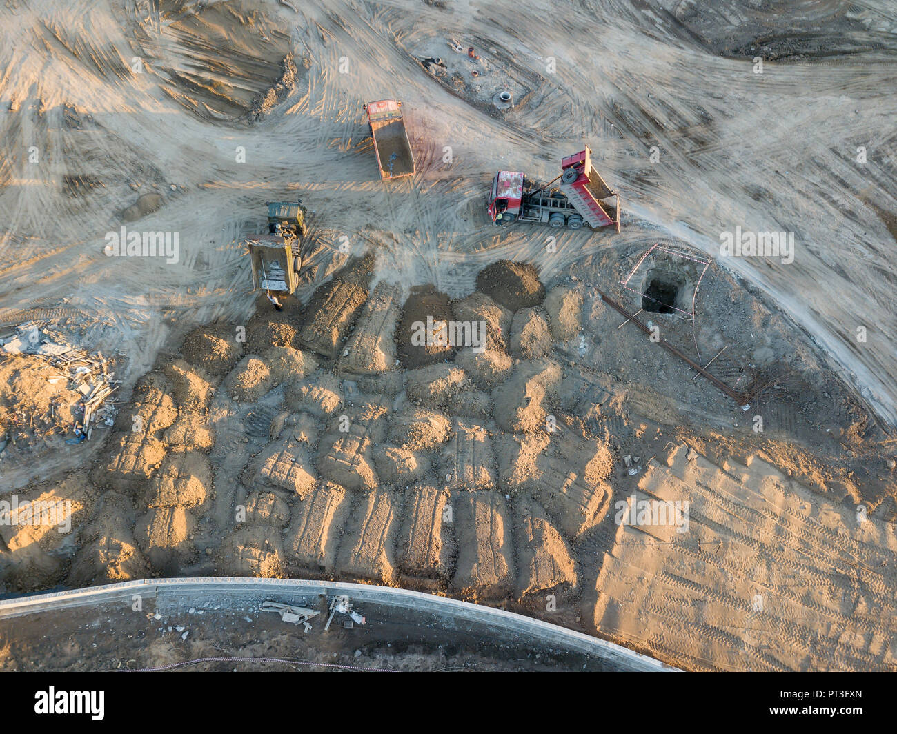 Aerial view of three multi-colored dump tip trucks unloading in a ...