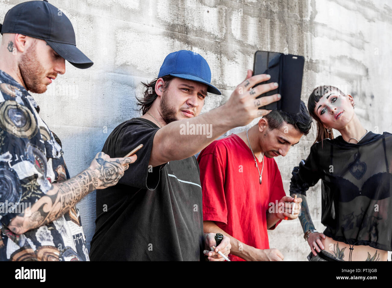 group of tattooed friends using smart phone against a gray wall over a ...