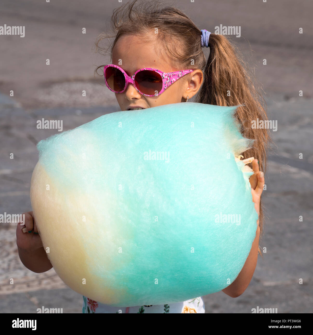 A little charming girl eating huge cotton candy Stock Photo - Alamy