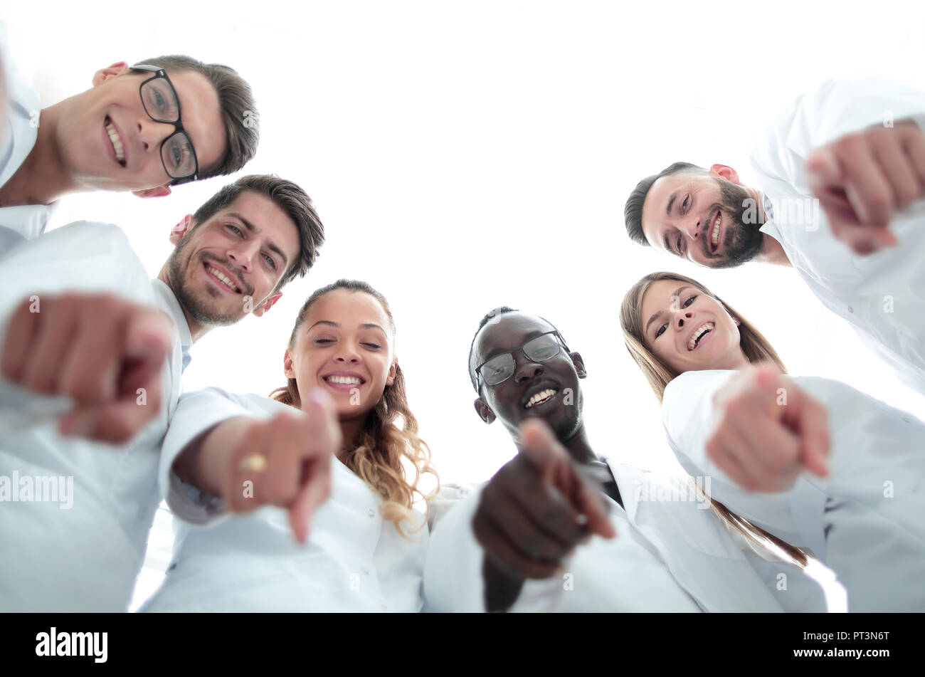 A group of young doctors points at the camera. View from below Stock ...