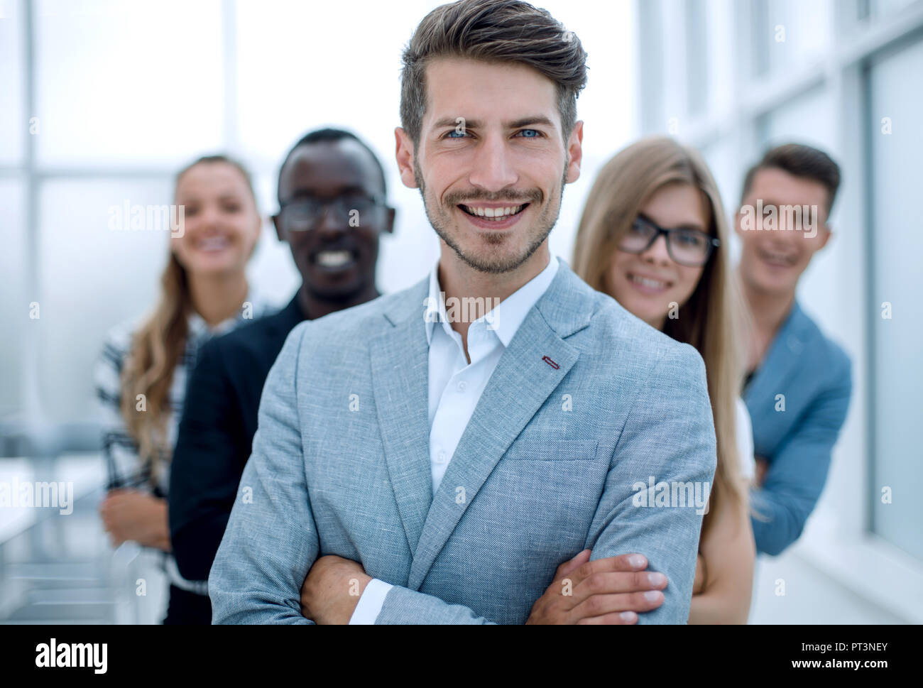 Young man with arms folded and friends behind him against a white ...